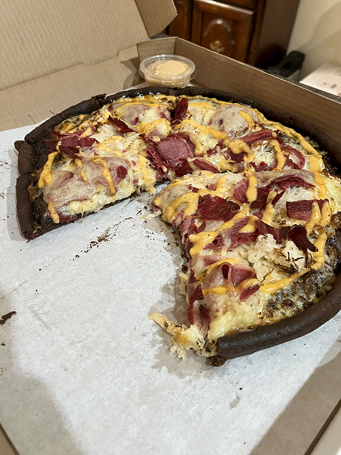The legendary Reuben pizza in all its glory—corned beef, sauerkraut, and thousand island drizzle creating a deli-pizza mashup that shouldn't work but absolutely does.