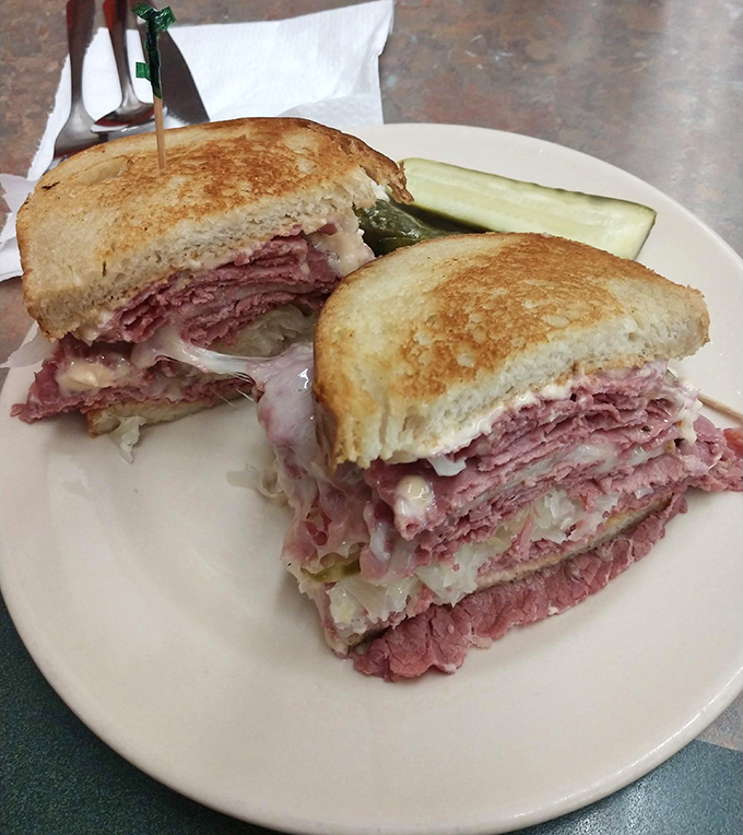 Behold the Reuben in its natural habitat&mdash;perfectly grilled rye, a mountain of corned beef, and sauerkraut applied by someone who understands proportion. That pickle isn't just a garnish, it's a necessity.