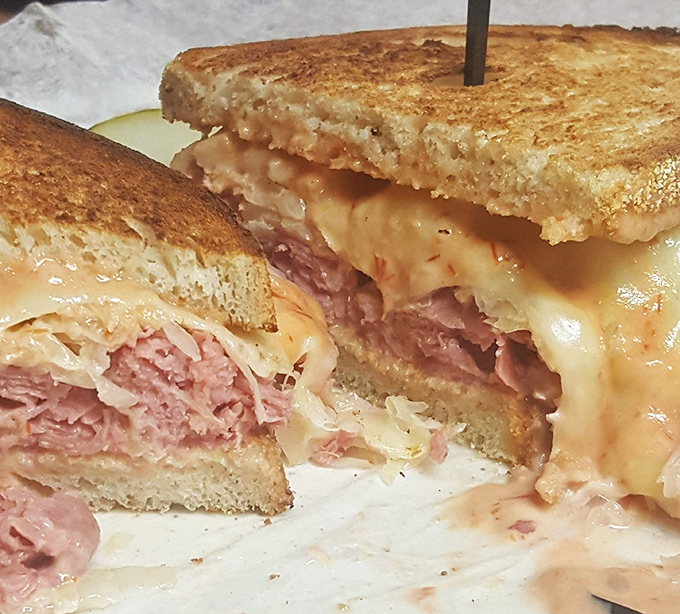 Behold the Reuben in its natural habitat: grilled, glorious, and gloriously messy, with cheese making a delicious escape attempt.
