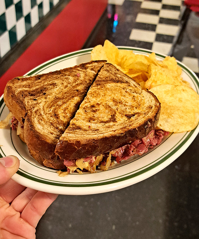 The star of the show: a perfectly grilled Reuben sandwich with corned beef stacked higher than your weekend plans, served with crispy potato chips.