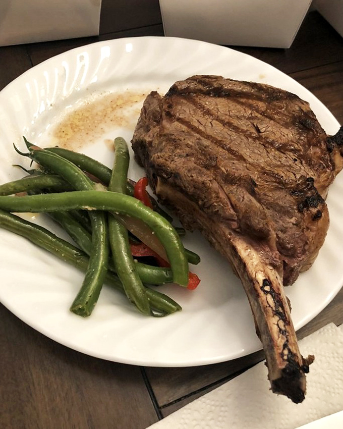 This bone-in ribeye isn't just dinner&mdash;it's a religious experience with green beans. The perfect char tells you someone in the kitchen really cares.