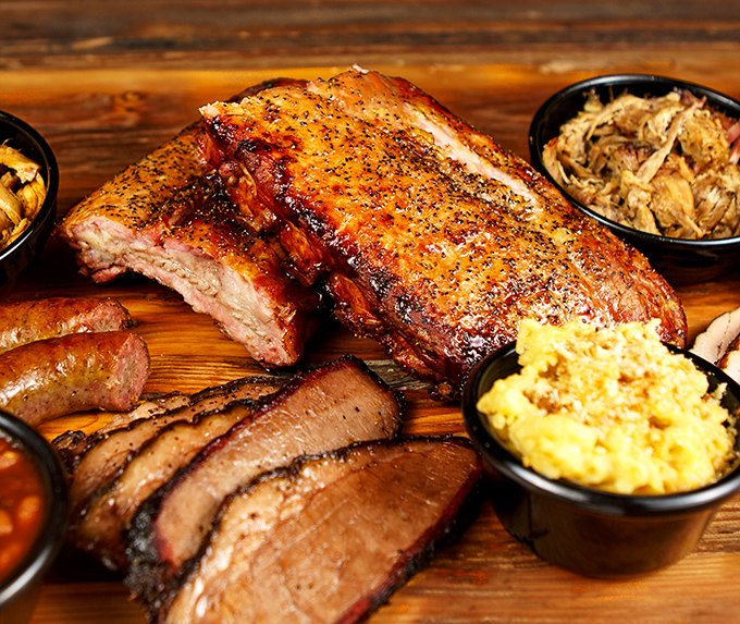 Behold the holy trinity of barbecue – ribs with that perfect pink smoke ring, brisket sliced against the grain, and sides that refuse to be upstaged.
