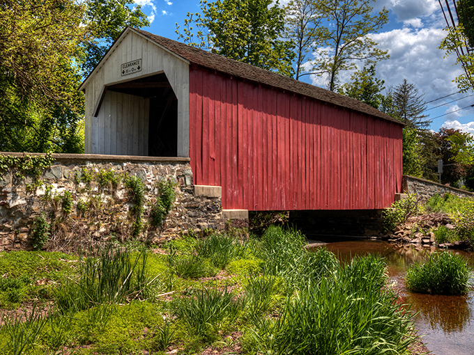 The bridge's striking red siding creates a perfect contrast against lush greenery, showcasing why covered bridges remain Pennsylvania's most photogenic transportation solution.