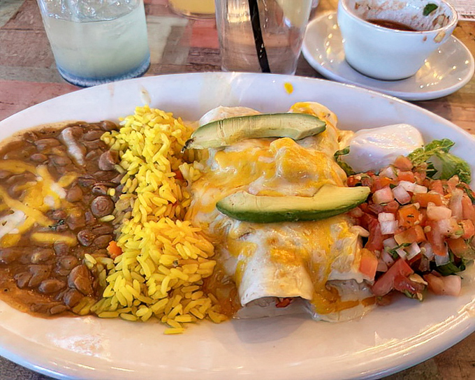Seafood enchiladas arrive like edible postcards from paradise – corn tortillas stuffed with ocean treasures, topped with melted cheese and fresh avocado slices.