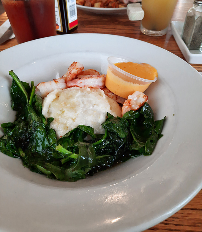 Shrimp nestled on a bed of vibrant greens with a perfectly poached egg&mdash;seafood breakfast that doesn't require an ocean view to be magnificent.
