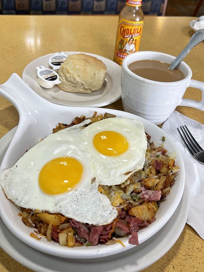 Two sunny-side-up eggs crown a mountain of home fries and ham &ndash; breakfast architecture that would make Frank Lloyd Wright proud.