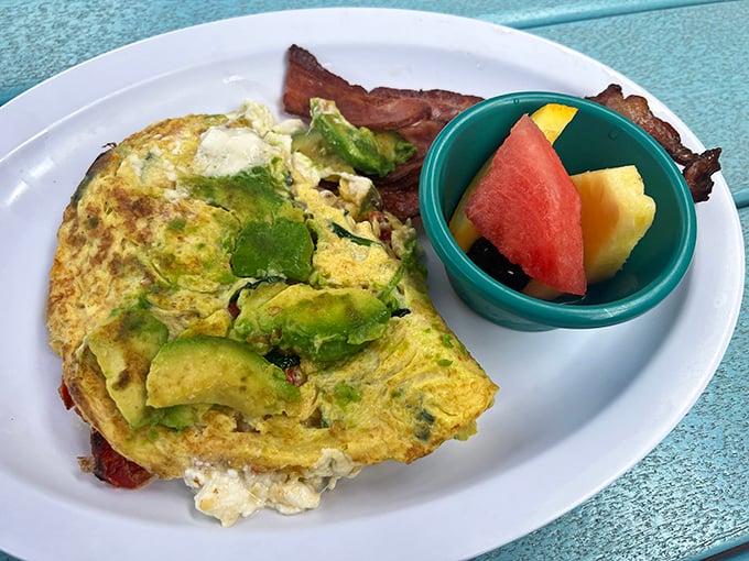 Green eggs without the ham! This avocado-stuffed omelet arrives with fresh fruit on the side, proving healthy choices can still be indulgent weekend pleasures.