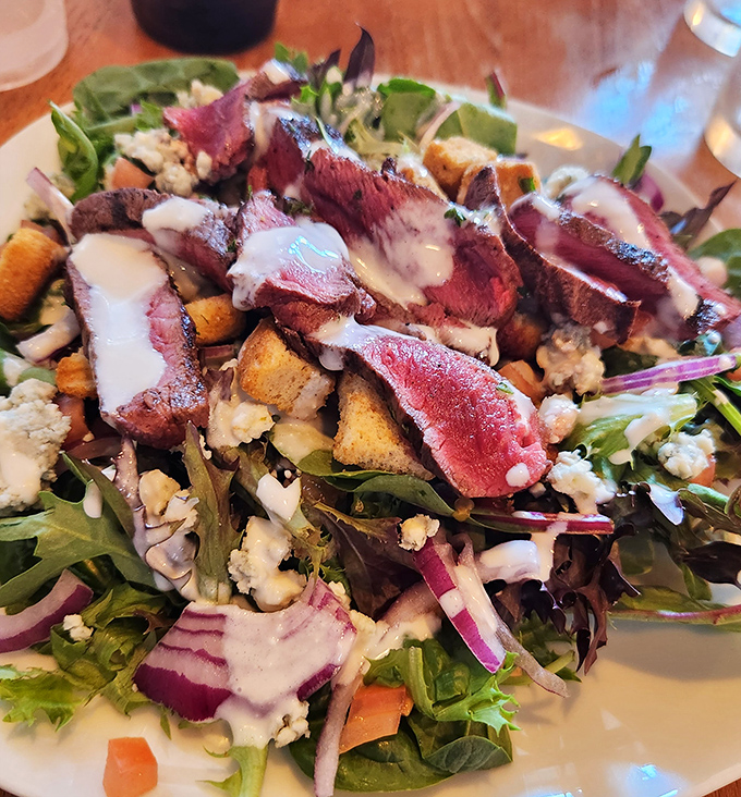 The legendary Black & Blue Steak Salad arrives like edible artwork&mdash;perfectly seared beef resting atop fresh greens with blue cheese crumbles playing hide-and-seek throughout.