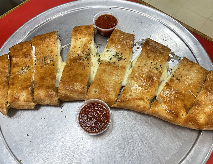 The star of the show: Villa Roma's stromboli, golden-brown and glistening, sliced into perfect portions with marinara dipping cups standing by for duty.