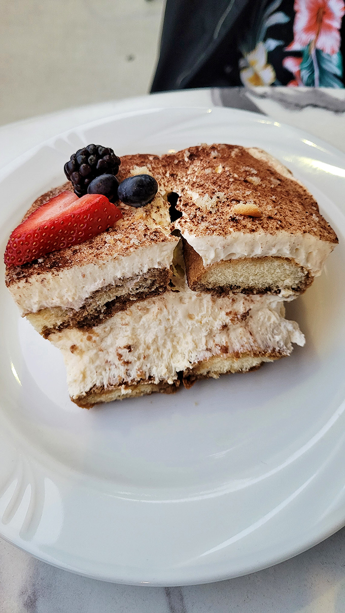 The legendary tiramisu arrives with fresh berries, its creamy layers promising the kind of bliss usually reserved for winning the lottery.