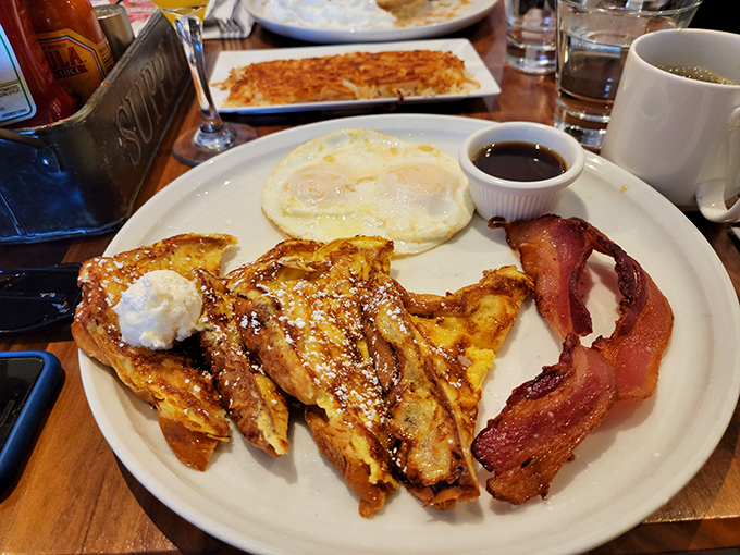 The legendary French toast combo&mdash;golden, crispy exterior giving way to custardy perfection, with eggs and bacon playing perfect supporting roles.