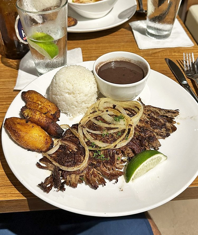 Behold the star attraction: vaca frita with its crispy edges, tender center, perfectly cooked plantains, and that lime wedge waiting to brighten everything.