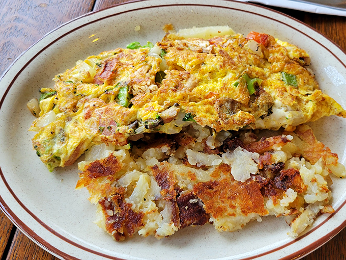 This omelet arrived looking like a fluffy sunset, packed with enough vegetables to justify dessert later.
