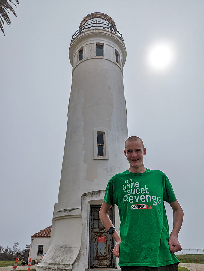 A visitor enjoys a moment with maritime history. Some people collect shot glasses from vacations; others collect lighthouse memories.
