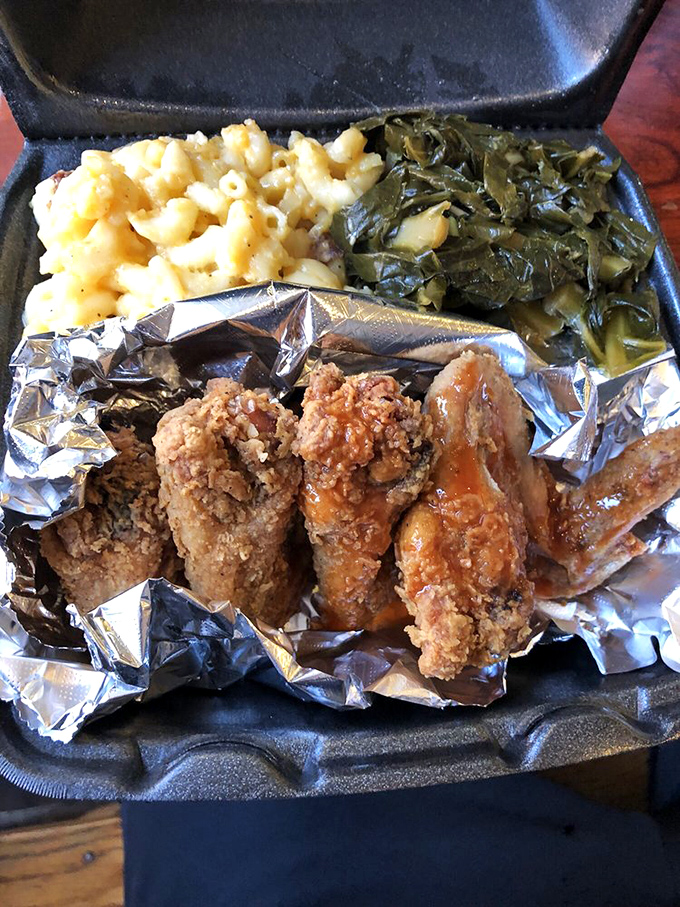 Golden fried wings nestled in foil like precious treasures, accompanied by mac and cheese perfection.