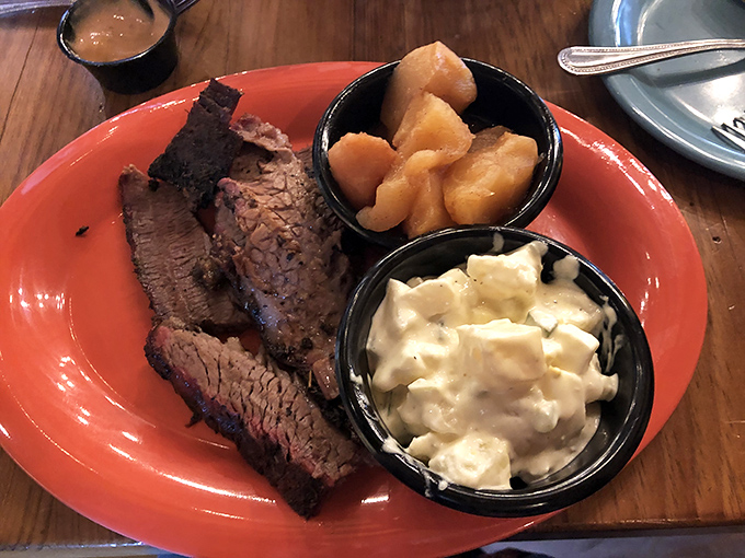 Behold the holy trinity of barbecue perfection: fork-tender brisket with that coveted smoke ring, alongside creamy mac and cheese and cinnamon apples.