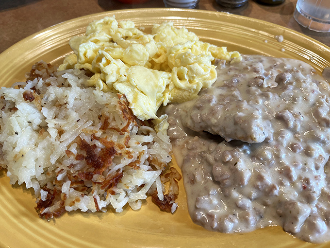 Behold the holy trinity of breakfast: creamy sausage gravy, golden hash browns, and fluffy scrambled eggs&mdash;a plate that whispers, "Good morning, beautiful."