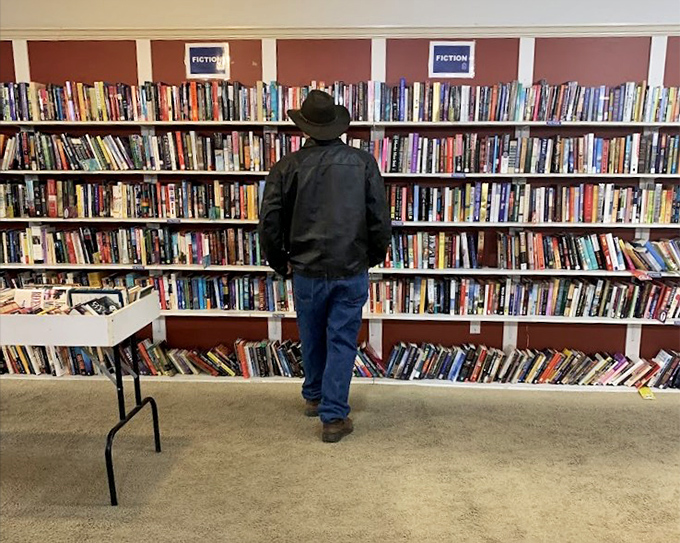 A gentleman browses fiction shelves that stretch like a literary buffet. Every book hunter knows this peaceful meditation.