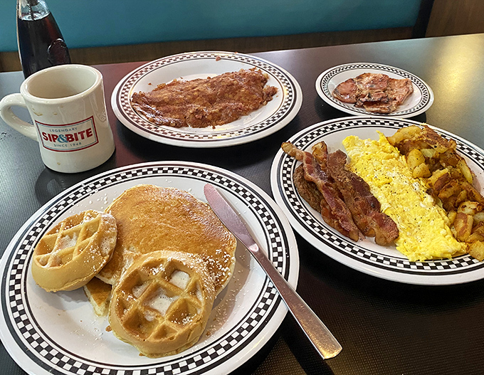 Breakfast nirvana achieved! Golden waffles dusted with powdered sugar alongside eggs and bacon that would make your cardiologist wince with delight.
