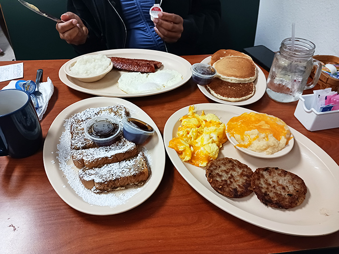 Breakfast spread that would make Ron Swanson weep with joy. French toast dusted with powdered sugar alongside eggs and sausage patties&mdash;morning nirvana.