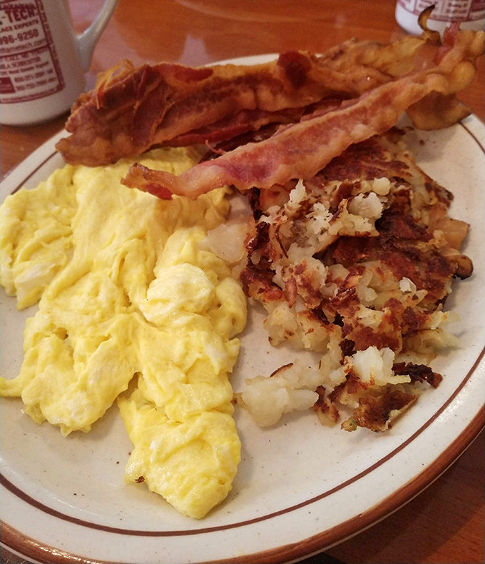 Breakfast nirvana achieved: fluffy scrambled eggs, perfectly crisped hash browns, and bacon that strikes the elusive balance between crisp and chewy. The holy trinity of morning meals.