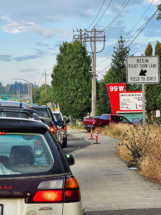The road to nostalgia is paved with anticipation. Cars queue up as the marquee promises an evening of entertainment under open skies.