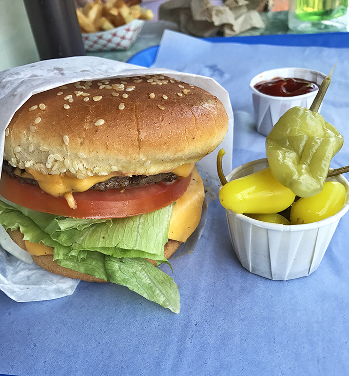 Behold the star of the show: a perfectly constructed cheeseburger with all the right accessories. Those pickles aren't just garnish&mdash;they're supporting actors deserving their own award.