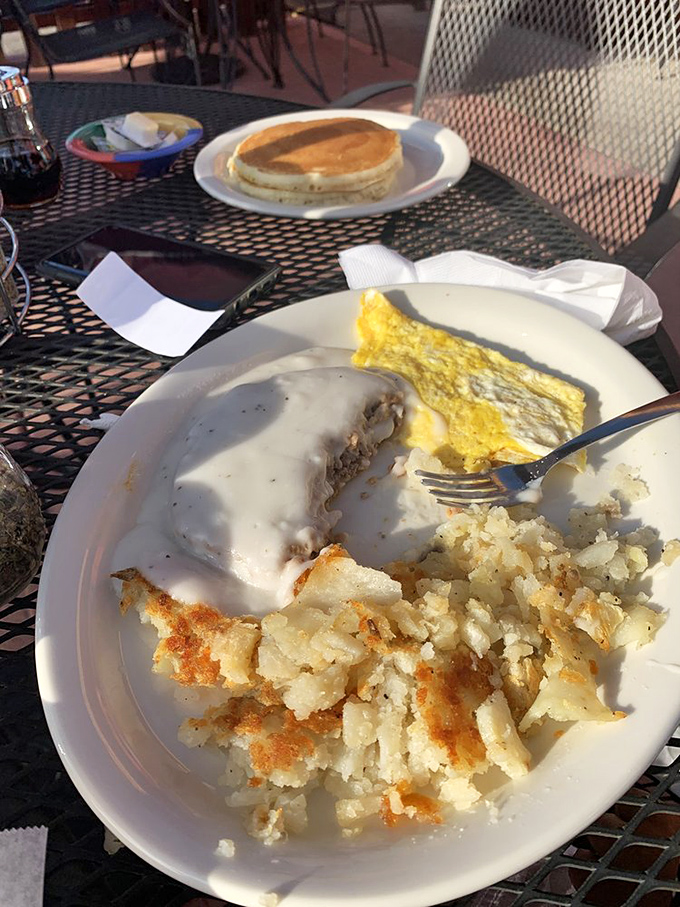 Behold the holy trinity of breakfast perfection: golden-crisp chicken fried steak smothered in pepper gravy, fluffy eggs, and home fries that demand attention.