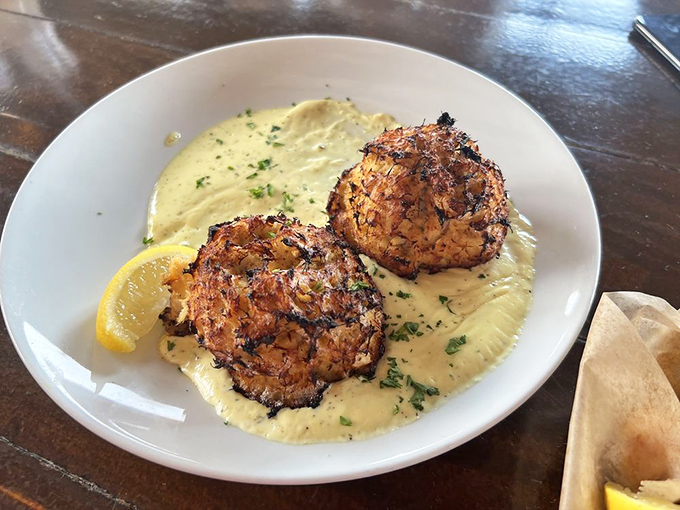 These crab cakes are what happens when jumbo lump crab decides it's too good for filler—pure seafood indulgence on a pool of heavenly sauce.