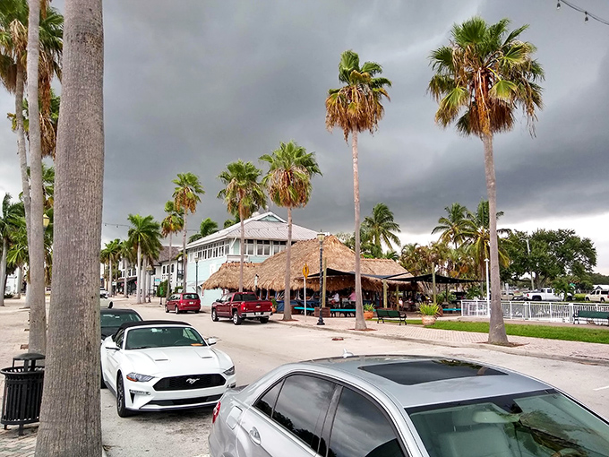 Stormy skies create dramatic backdrops for Fort Pierce's charming streetscape, where palm trees stand sentinel over tiki-roofed escapes from reality.