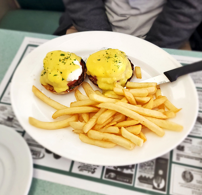 Eggs Benedict that would make the Pope jealous. Those golden hollandaise cascades are performing gravity-defying miracles while the fries stand by as worthy witnesses.
