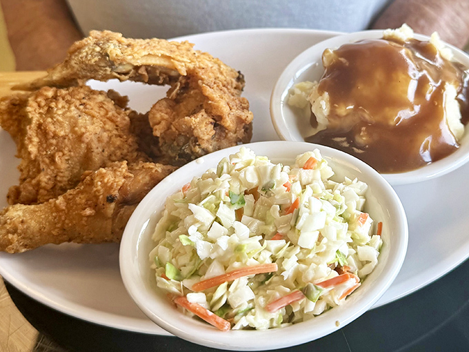 Golden-brown chicken with that perfect crackle-when-you-bite-it skin, flanked by creamy coleslaw and mashed potatoes drowning in gravy—a holy trinity of comfort.