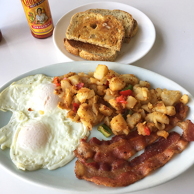 The holy trinity of breakfast perfection: eggs cooked just right, crispy bacon, and country potatoes that could make a hash brown jealous.