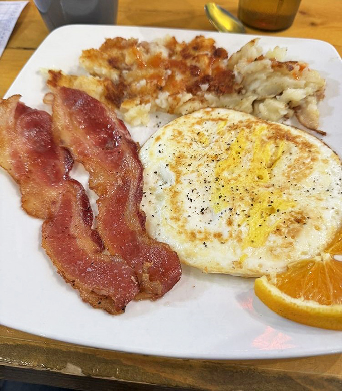 The holy trinity of breakfast: a perfectly fried egg, crispy bacon, and home fries that could make a potato proud.