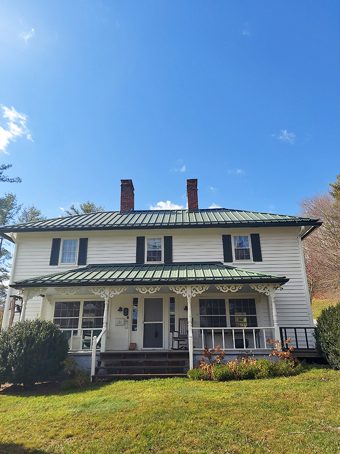 This historic white farmhouse whispers stories of mountain life from another era, its green metal roof nodding to both tradition and practicality.