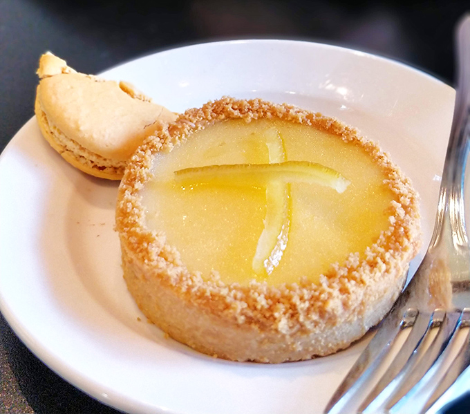 The legendary lemon tart, with its perfect balance of sweet and tart, sits beside a macaron like royalty holding court with a loyal subject.