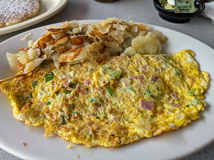 This omelet doesn't just sit on the plate &ndash; it sprawls luxuriously beside golden hash browns that crackle with each forkful.