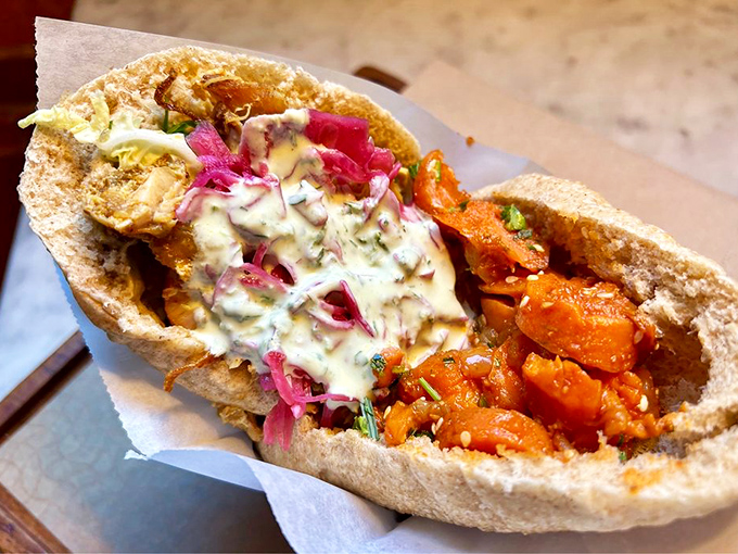 This isn't just a pita sandwich&mdash;it's an edible color wheel of vibrant pickled onions, roasted vegetables, and creamy sauce that makes your standard lunch weep with inadequacy.
