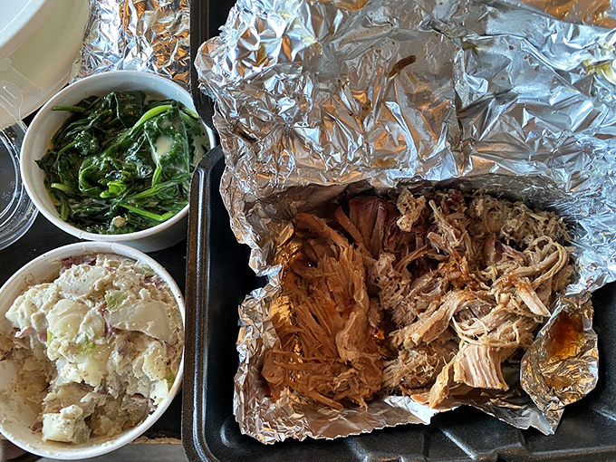 Tender strands of pulled pork nestled in foil, ready to transport you to flavor country alongside those perfectly prepared sides.