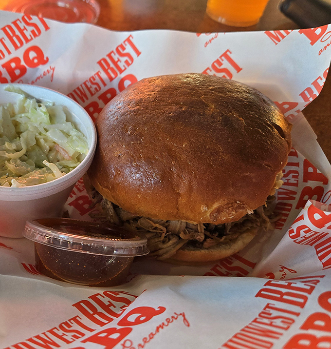 The pulled pork sandwich in its natural habitat &ndash; a golden-brown bun cradling a generous heap of smoky perfection with slaw standing by.