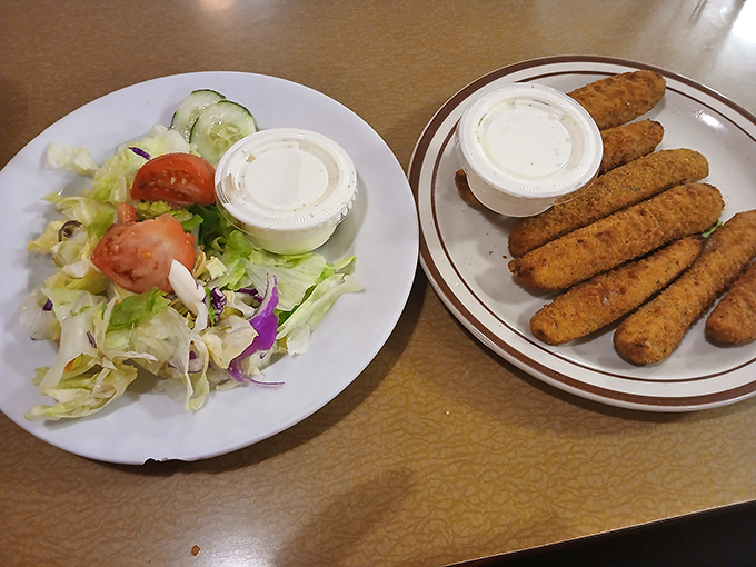 A side salad that actually tries! Crisp lettuce, fresh veggies, and those golden mozzarella sticks standing at attention like delicious sentinels.