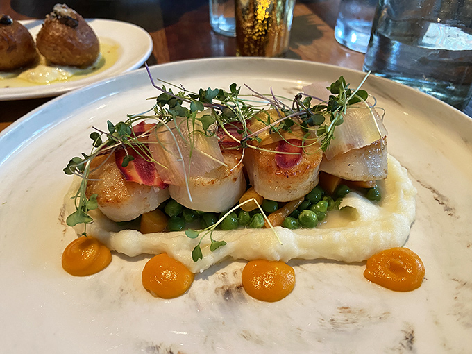 These scallops aren't just seared&mdash;they're transformed into buttery medallions of joy, perched atop a cloud of pur&eacute;e with colorful accents that pop like edible confetti. 