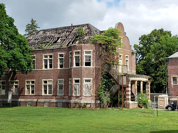 Nature slowly reclaims what humans abandoned, with vines creeping up the brick fa&ccedil;ade like fingers trying to pull the building back into the earth.