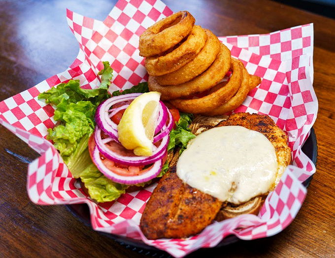 A blackened fish sandwich that doesn't need ocean views to taste authentic. Those onion rings stacked like a delicious game of Jenga seal the deal.