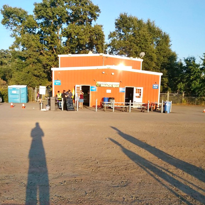 The bright orange snack bar stands like a beacon of buttery promise, where movie munchies await and the aroma of popcorn travels on evening breezes.