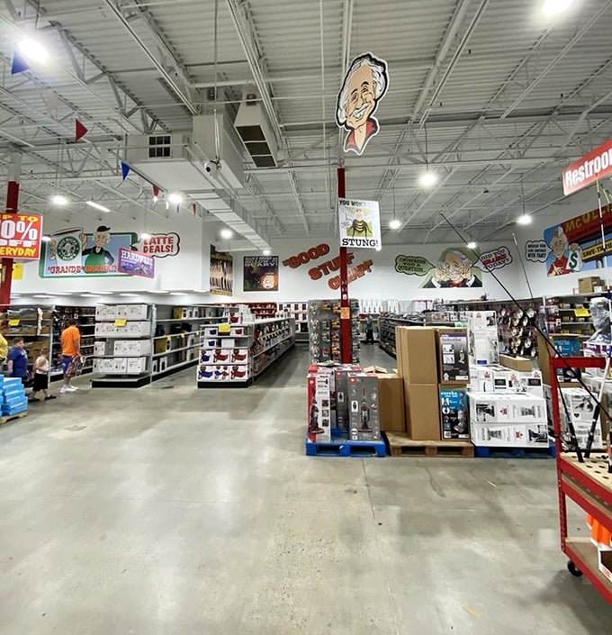 Overhead, Ollie's cartoon mascot watches over shoppers navigating the organized chaos of discounted merchandise below.