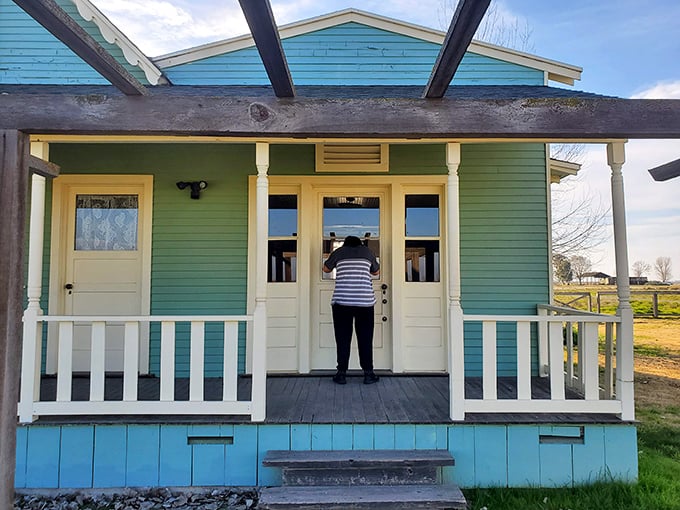 A visitor peers into the past through the turquoise-framed doorway, where history isn't just preserved&mdash;it's waiting to be experienced firsthand.