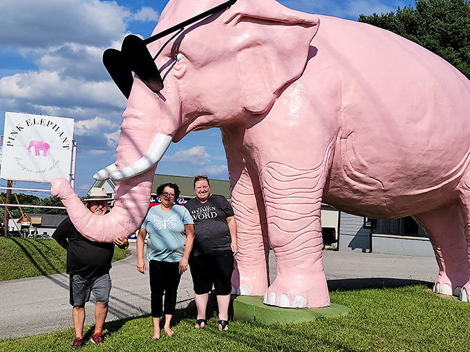Visitors gather beneath Ellie's massive frame, providing perfect scale to appreciate just how impressively large this pink pachyderm truly is.