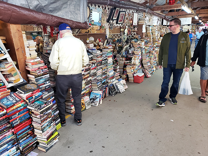 Books tower in literary mountains while shoppers dig for their next great read or hidden gem.