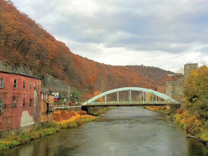 Oil City&rsquo;s arched bridge spans the Allegheny River, framed by autumn hillsides and weathered brick reminders of the city&rsquo;s industrial past.